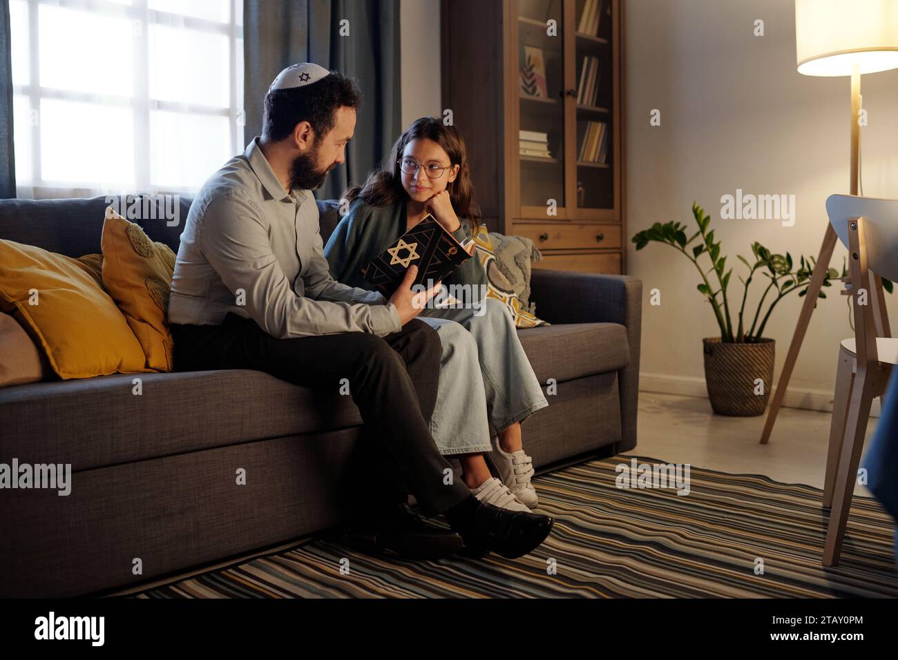 Cute girl listening to her father wearing kippah during discussion of ...