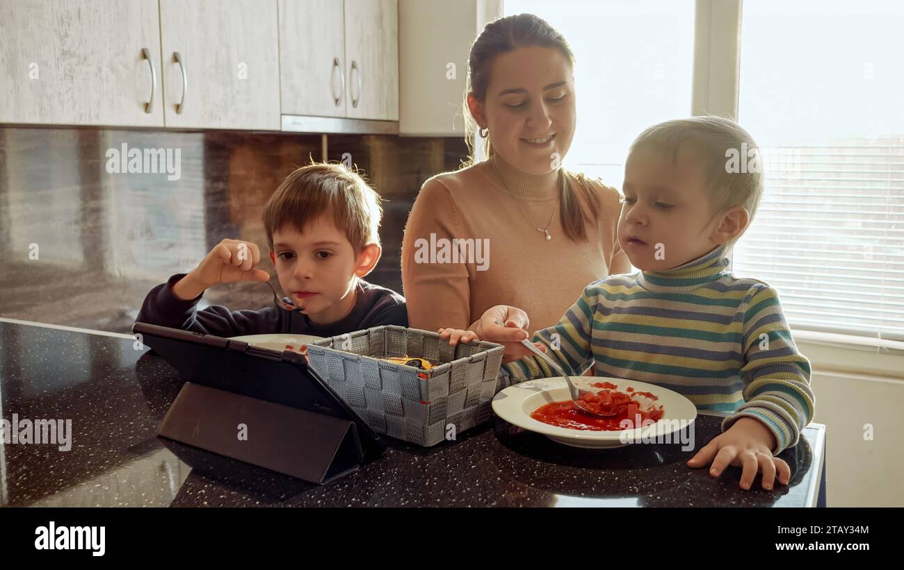 Happy family with children having soup for dinner on kitchen. Domestic ...