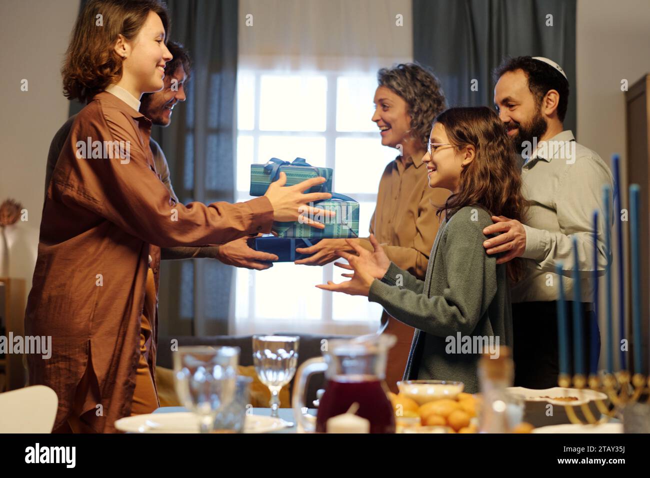 Happy Jewish family of five giving presents to one another while ...