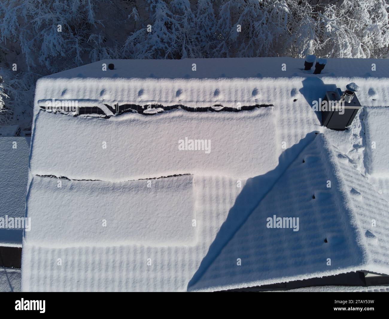 Snow blankets solar panels on a house roof in winter. Despite the ...
