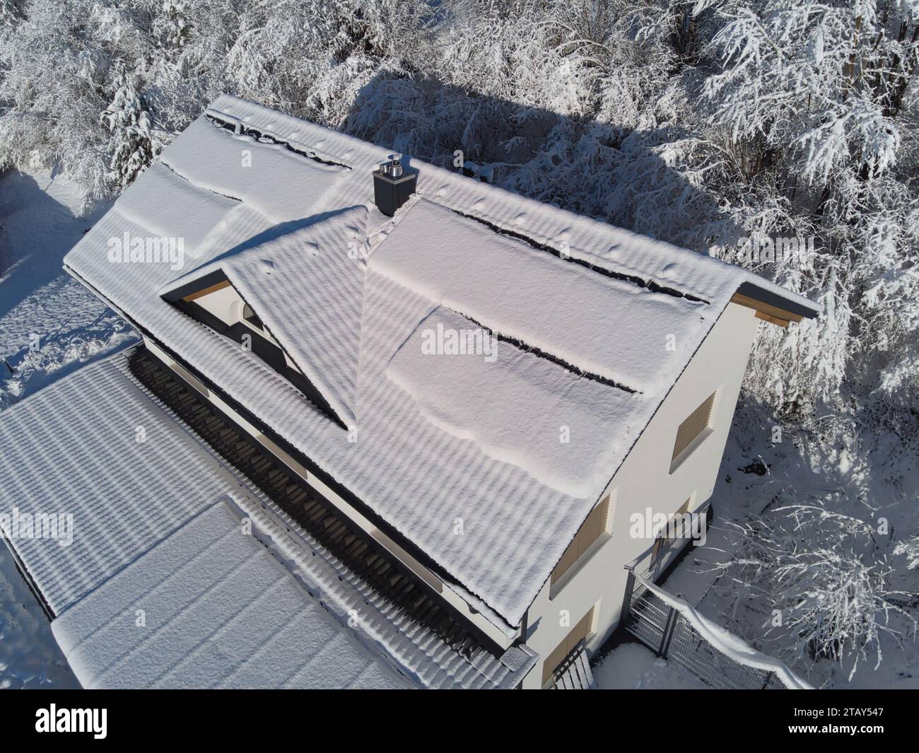 Snow blankets solar panels on a house roof in winter. Despite the ...