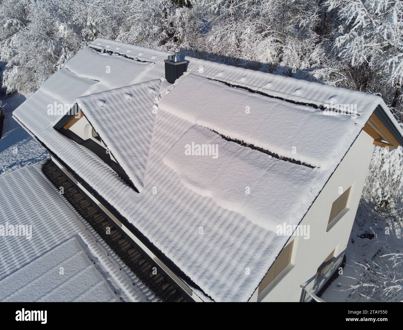 Snow blankets solar panels on a house roof in winter. Despite the ...