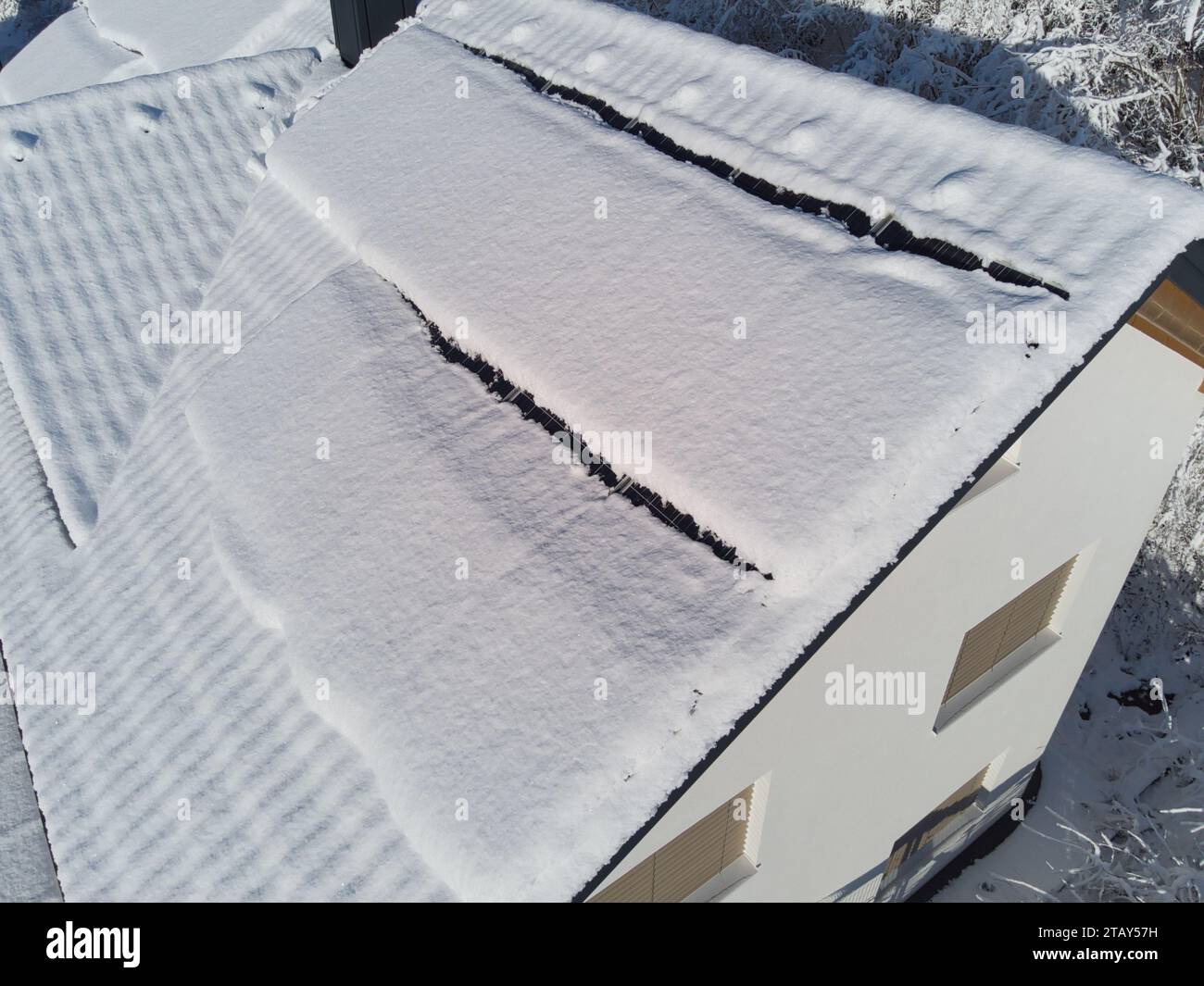 Snow blankets solar panels on a house roof in winter. Despite the ...