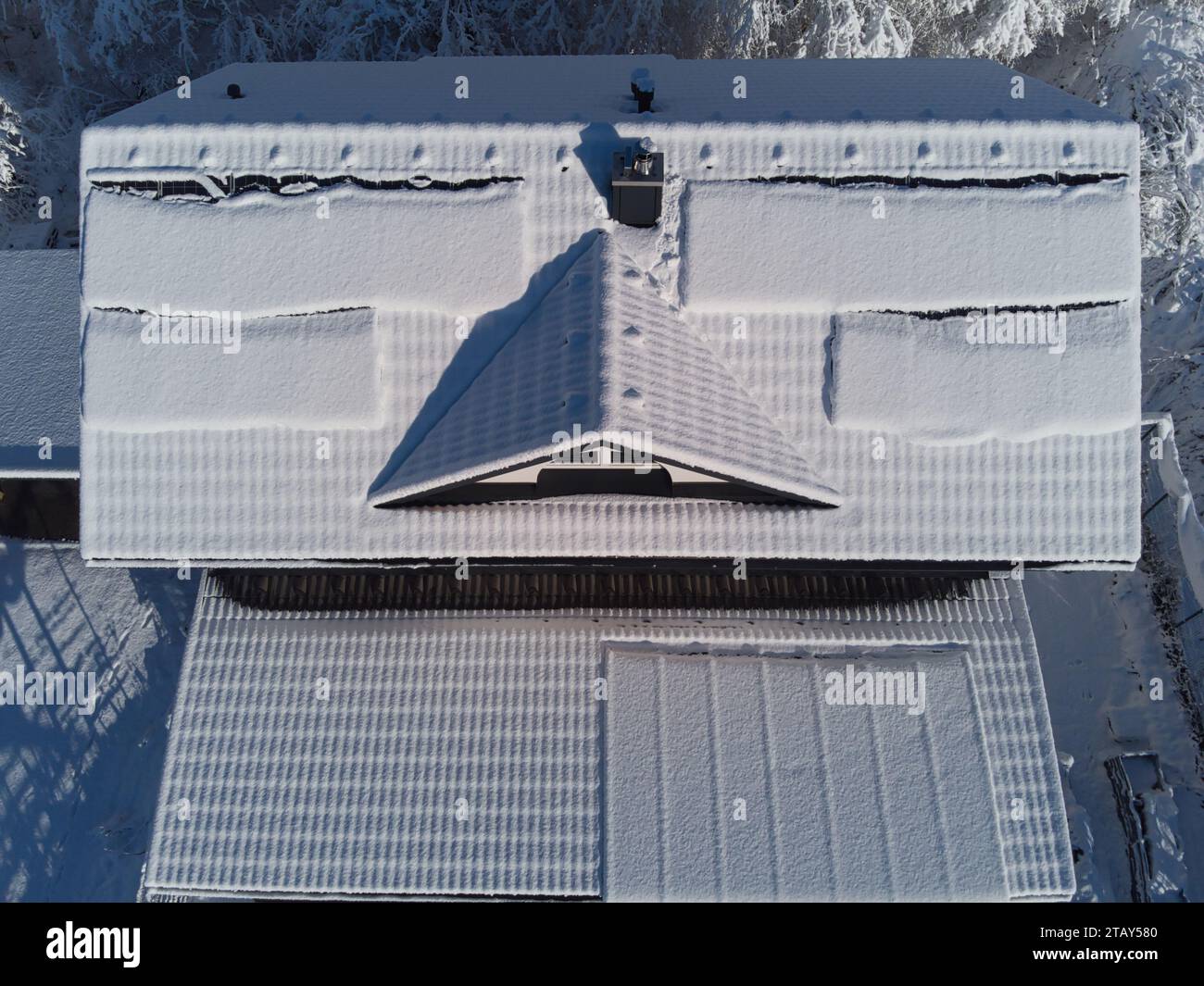 Snow blankets solar panels on a house roof in winter. Despite the ...