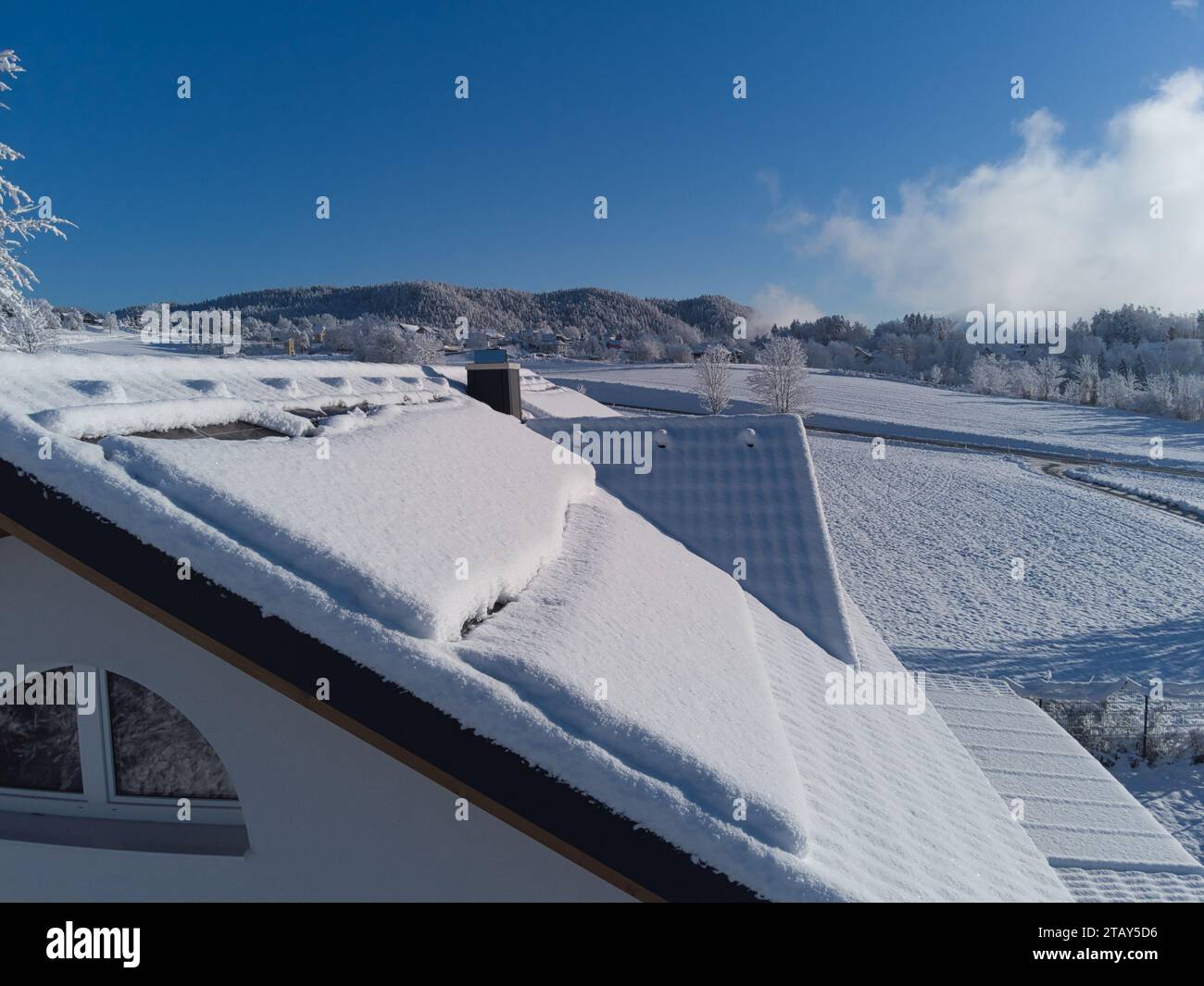 Snow blankets solar panels on a house roof in winter. Despite the ...