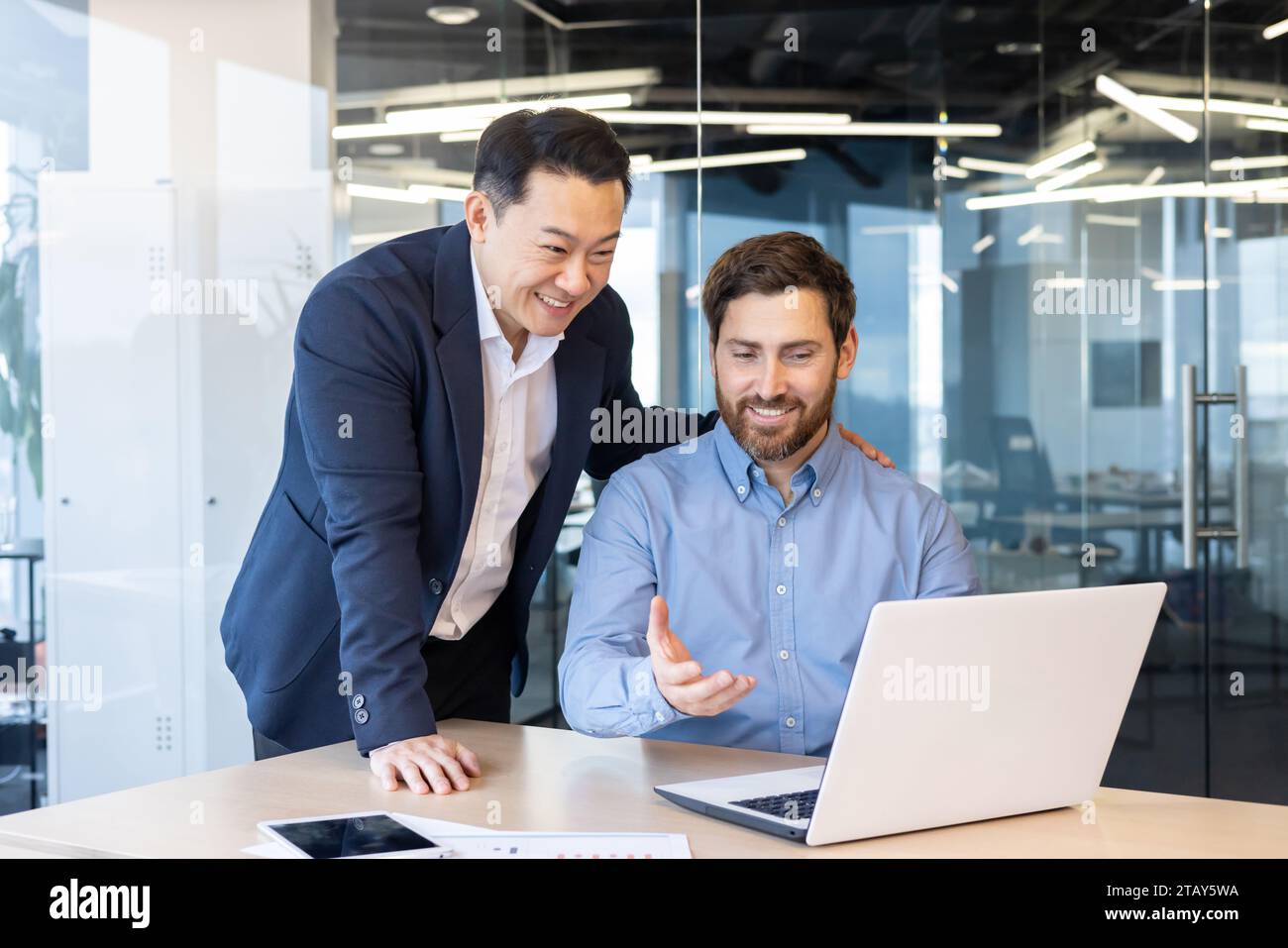 Asian senior boss helping colleague on new employee at workplace inside ...