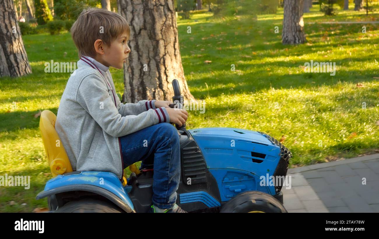 Happy boy riding on toy tractor at park. Kids playing in park, farming ...