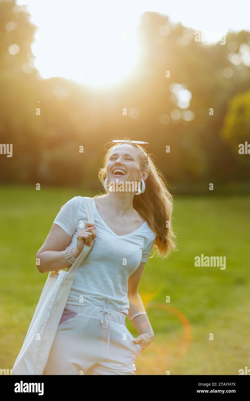 Summer time. happy stylish 40 years old woman in white shirt with tote ...