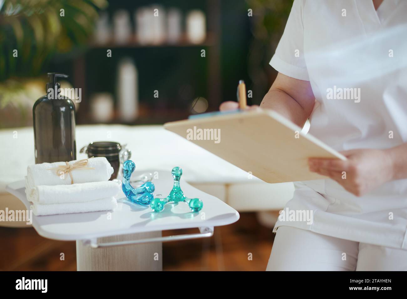 Healthcare time. Closeup on female medical massage therapist in massage cabinet with clipboard ...
