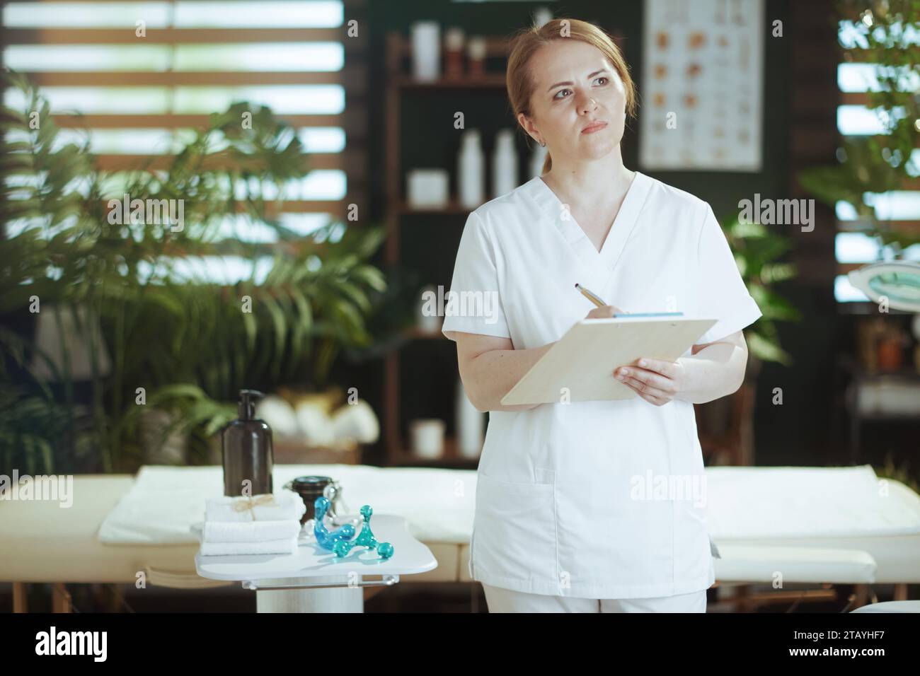 Healthcare time. female medical massage therapist in spa salon with clipboard Stock Photo - Alamy