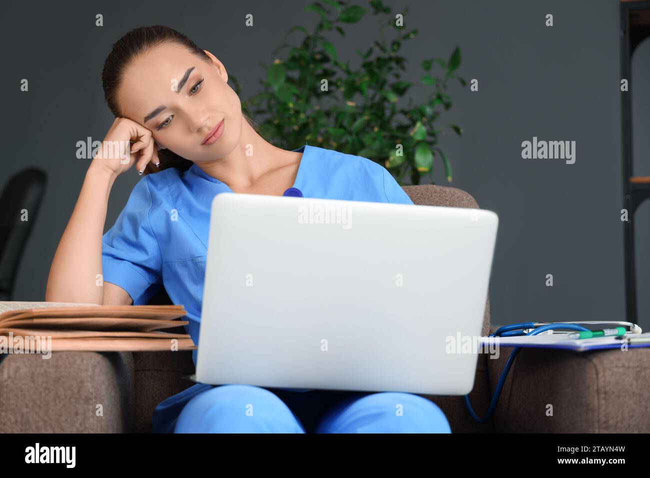 Tired female medical student studying with laptop in library Stock ...