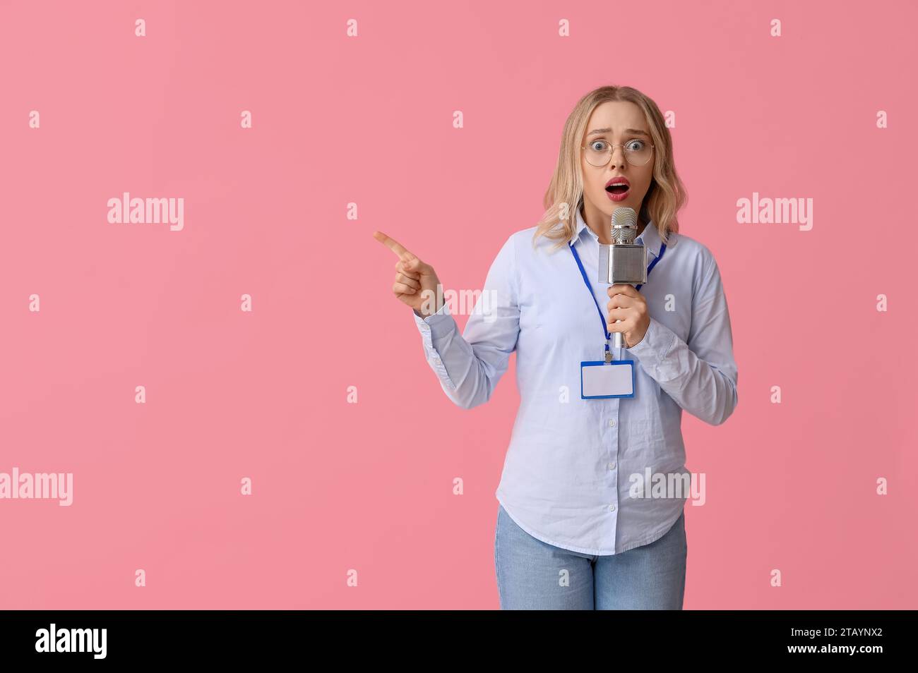 Portrait of shocked female journalist with microphone pointing at ...