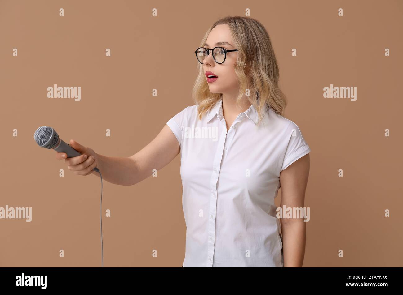 Portrait of shocked female journalist with microphone taking interview ...
