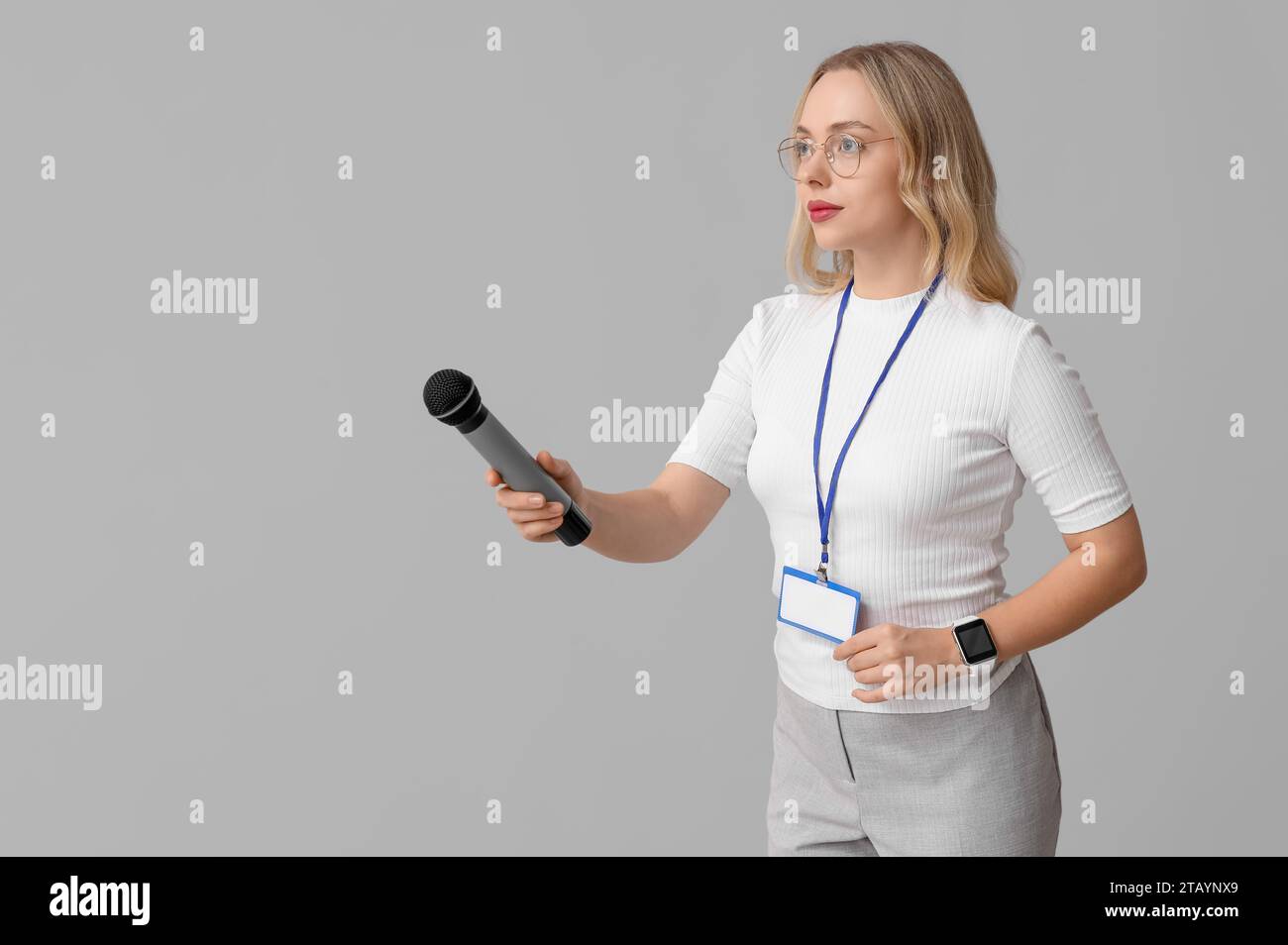 Portrait of female journalist with microphone taking interview on grey ...