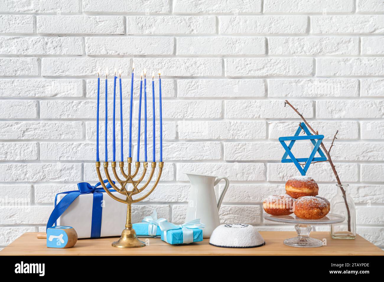 Wooden table with decorations for Hanukkah celebration near white brick ...