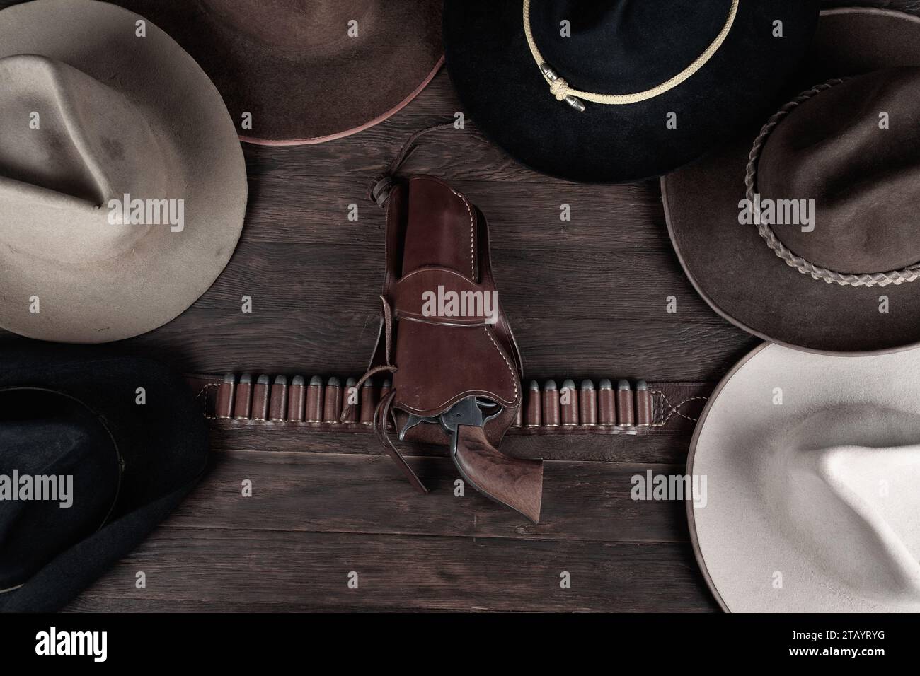 Gun with holster and gun belt with old west hats on wooden table. Top ...