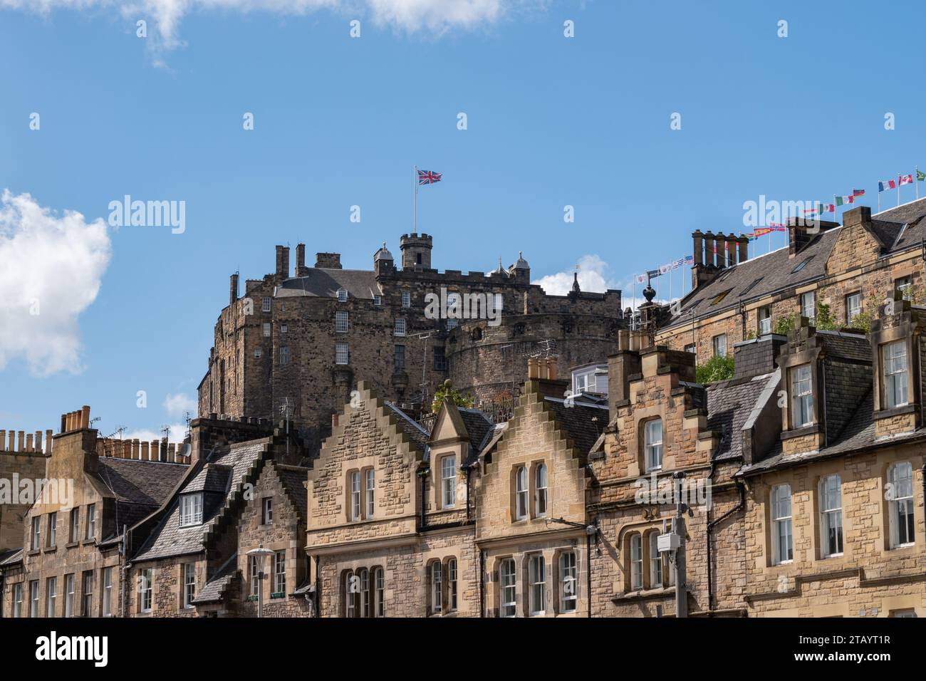 Row of old stone buildings with a castle backdrop and blue sky along ...
