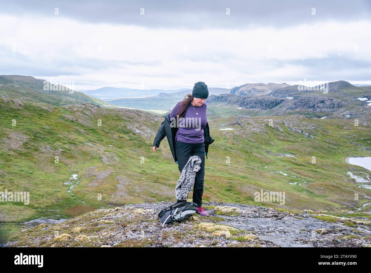 Mature woman is going to dress up with warmer clothes, hiking at high ...