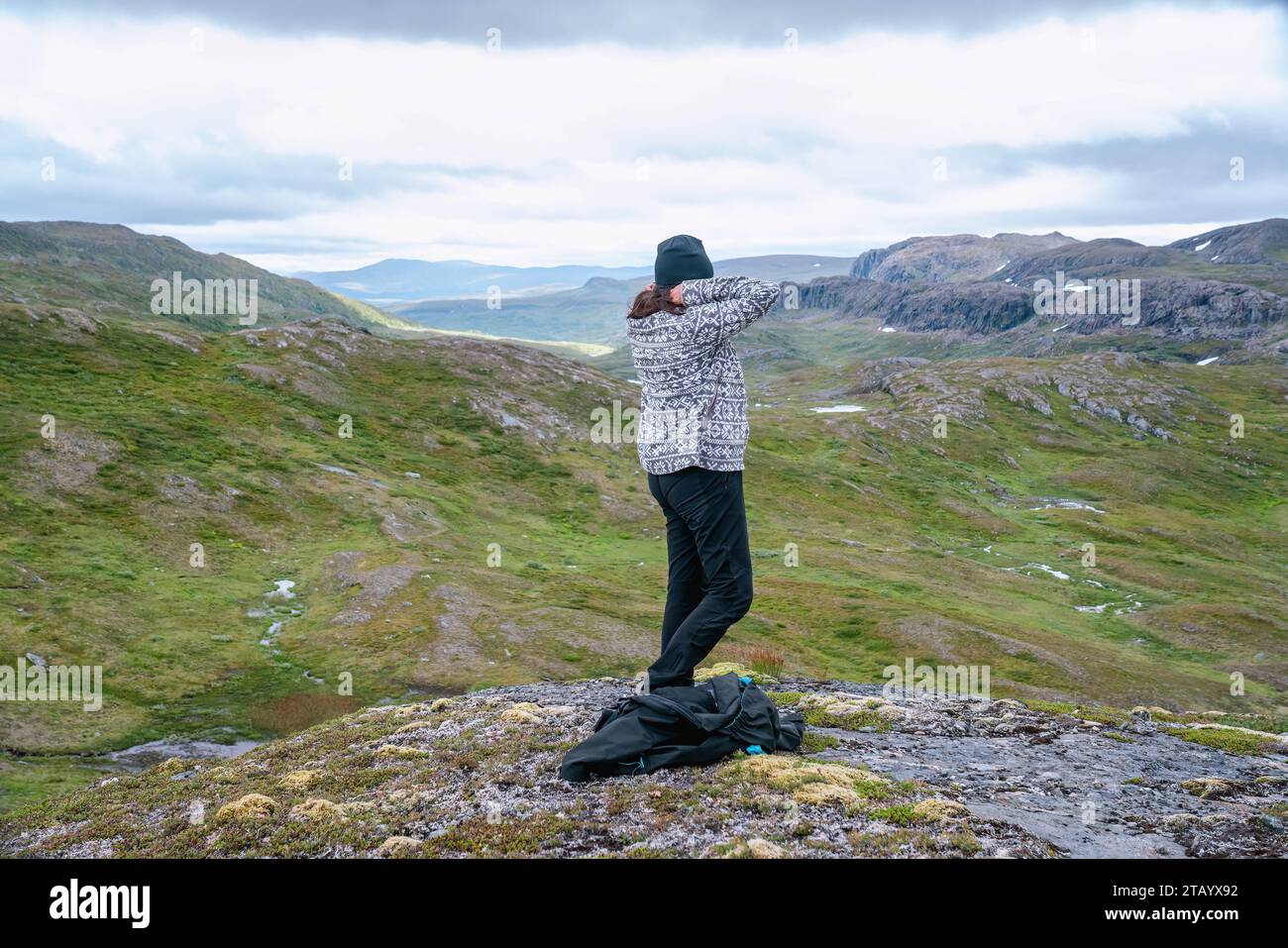 Mature woman adjusts warmer clothes, hiking at high altitude cold ...