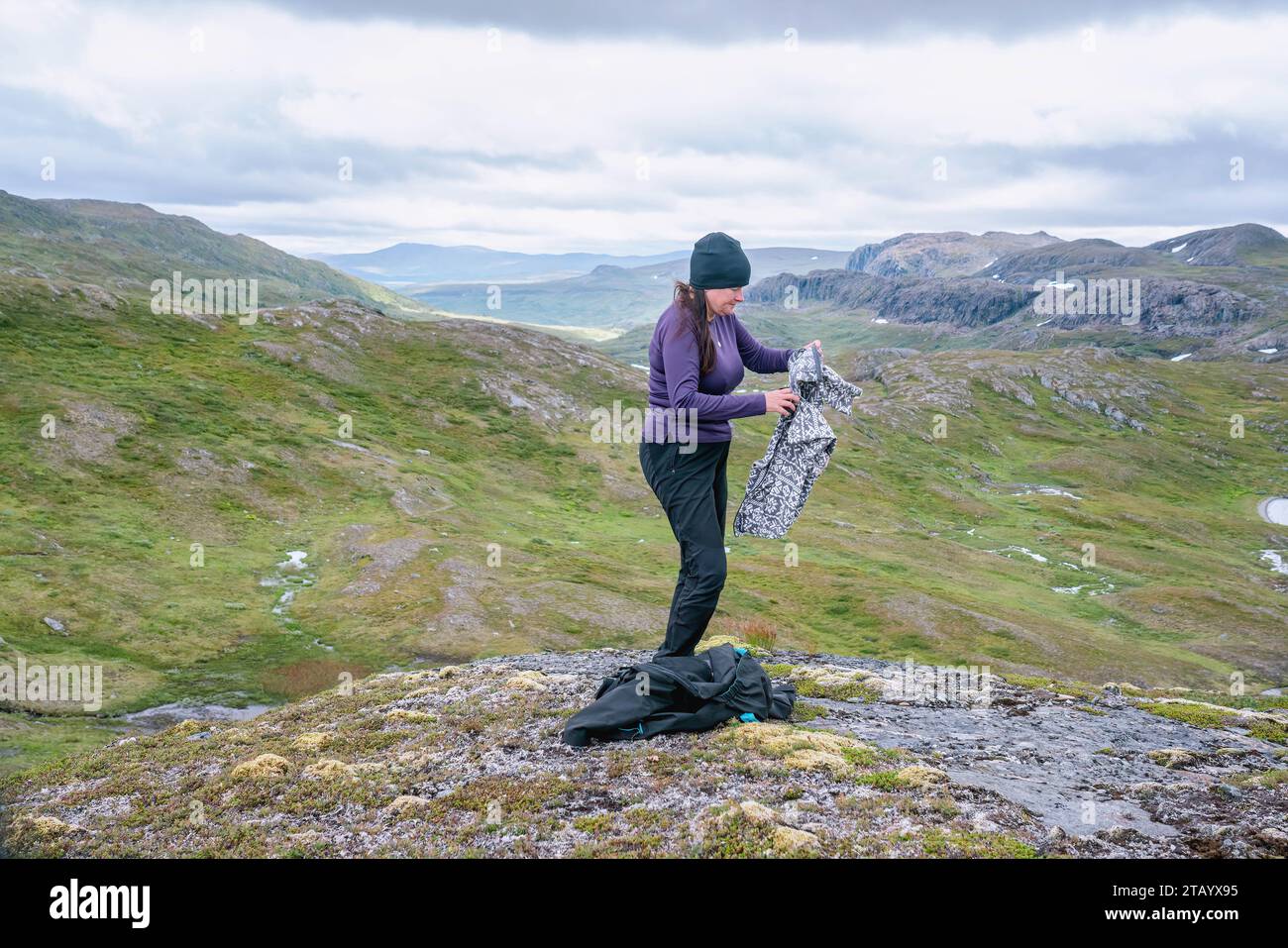 Mature woman is taking warmer clothes, hiking at high altitude cold ...