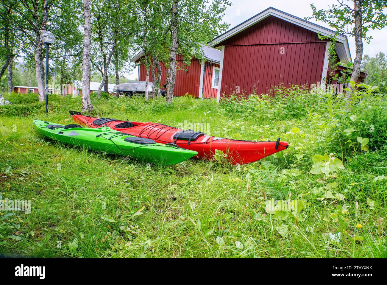 Two kayaks - red and green ones are on the green grass, low level side ...