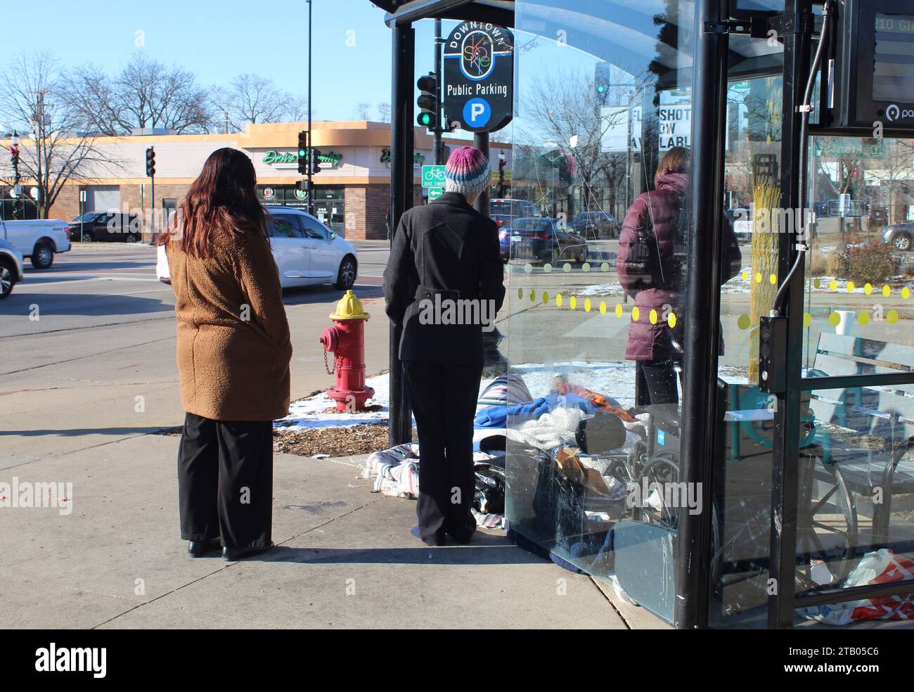 Three social workers speaking to a homeless man living in a bus shelter ...