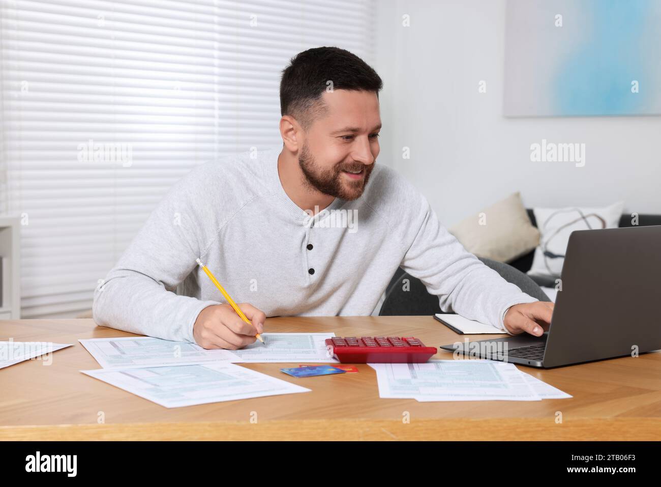 Man doing taxes at table in room Stock Photo - Alamy