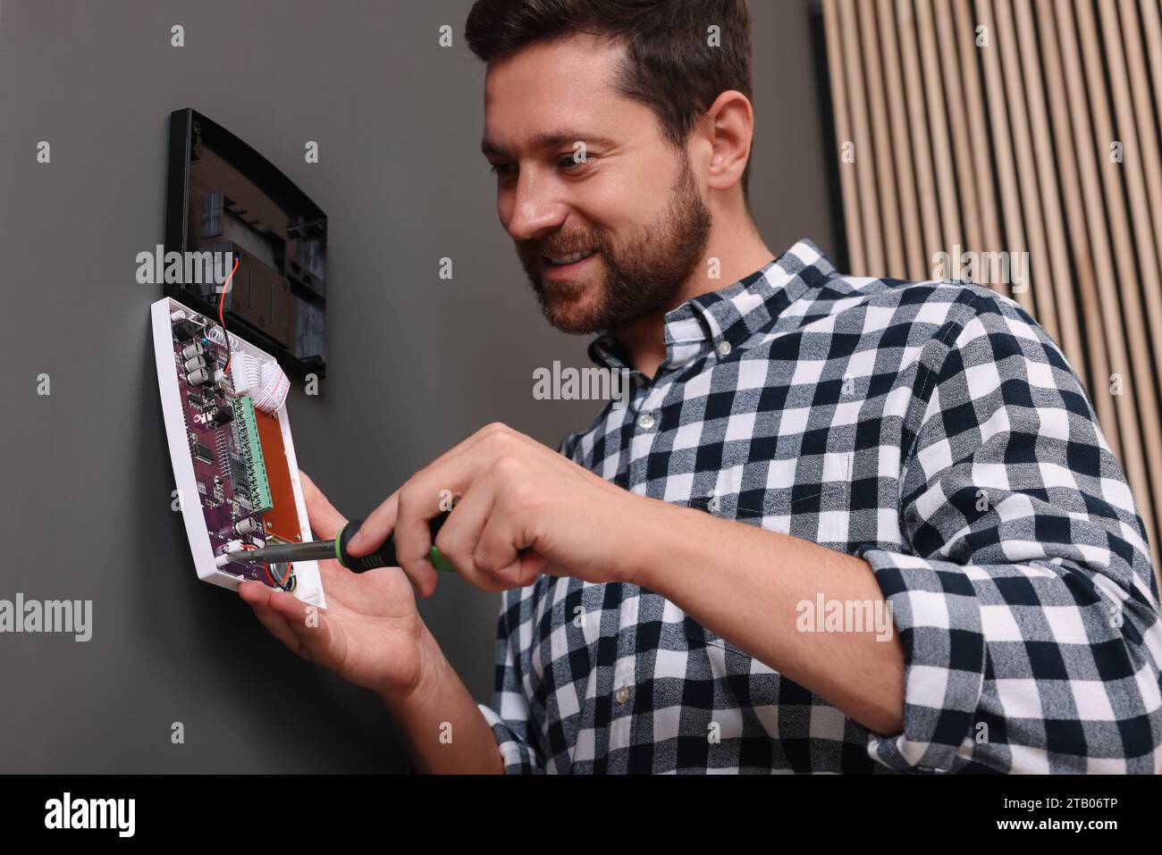 Man installing home security alarm system on gray wall Stock Photo - Alamy