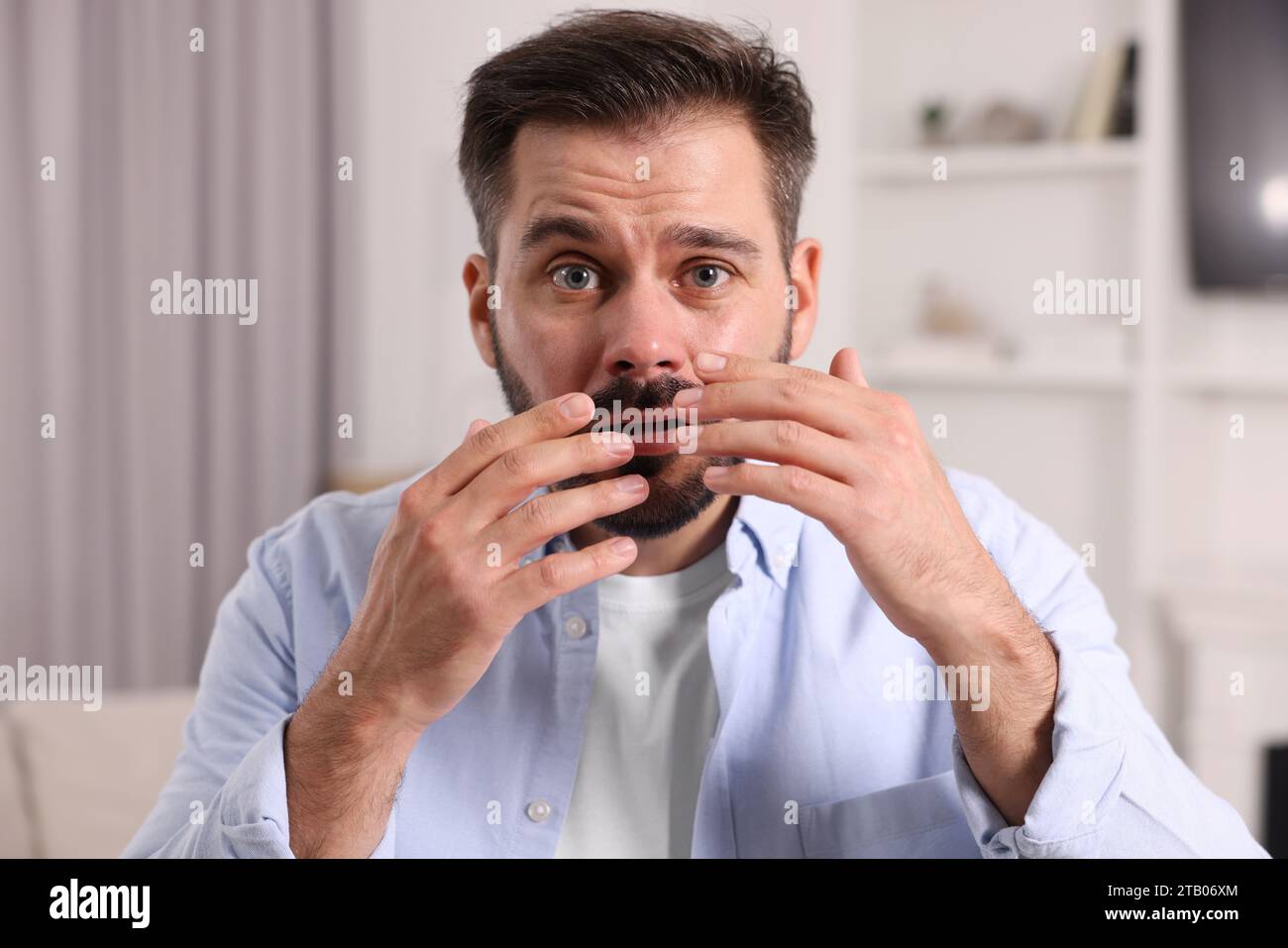 Skin problem. Confused man touching his face at home Stock Photo - Alamy