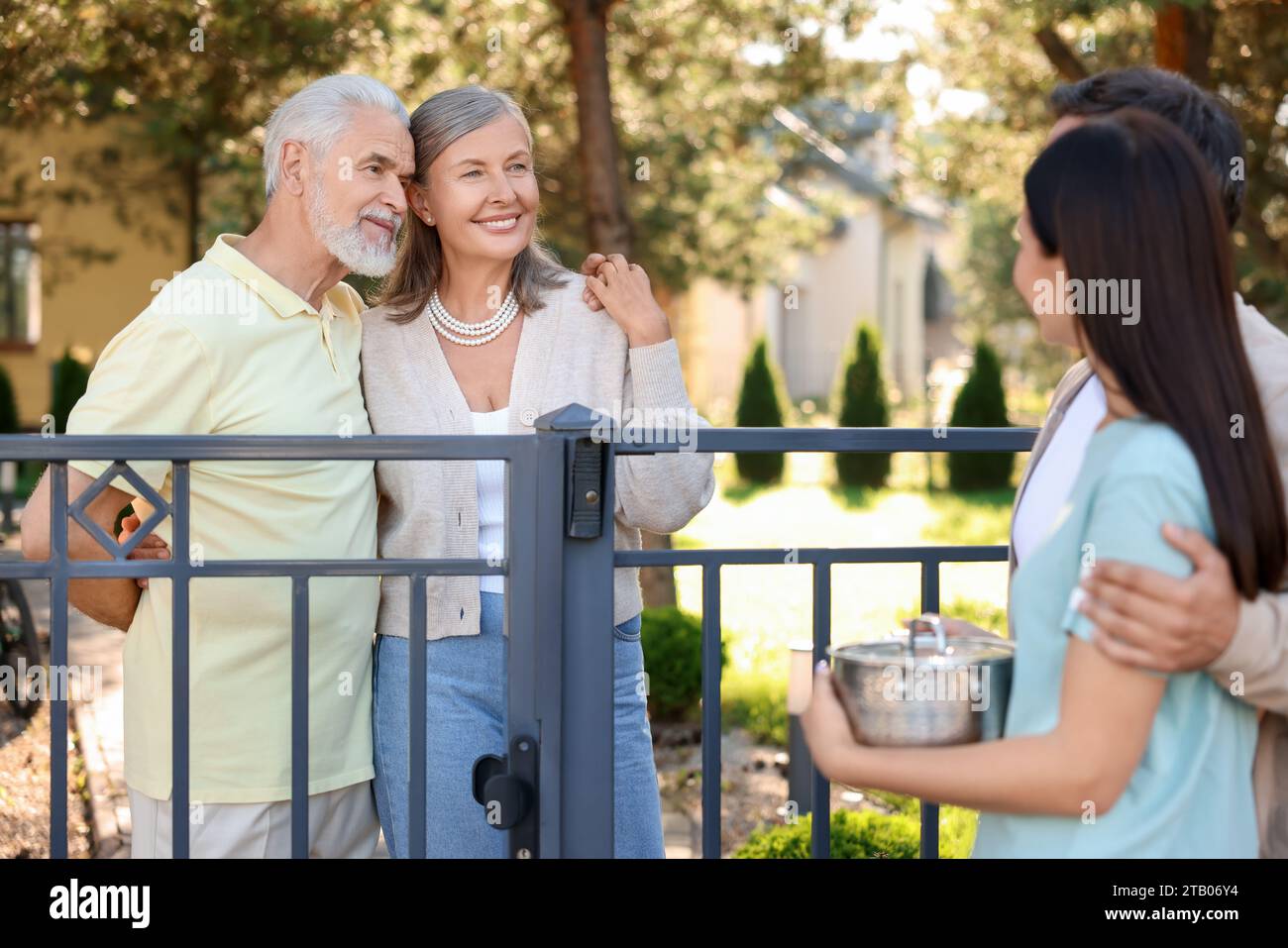 Friendly relationship with neighbours. Young family talking to elderly ...