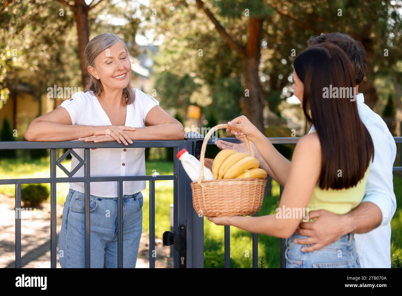 Friendly relationship with neighbours. Young couple with wicker basket ...