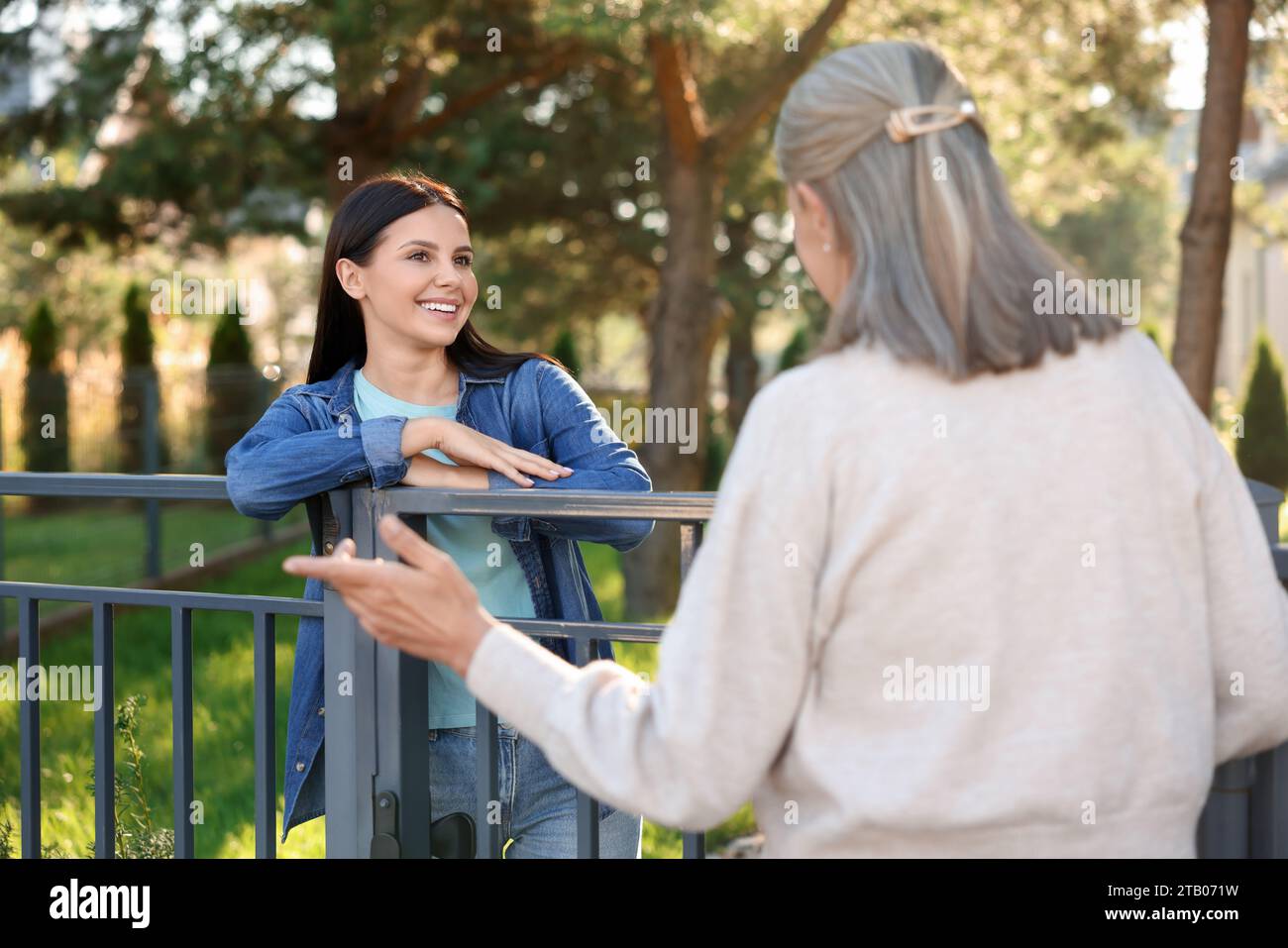 Friendly relationship with neighbours. Happy women talking near fence ...