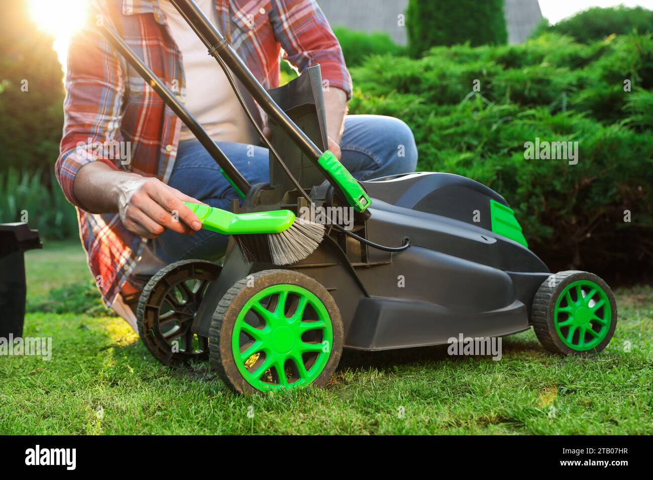 Man cleaning lawn mower with brush in garden, closeup Stock Photo - Alamy