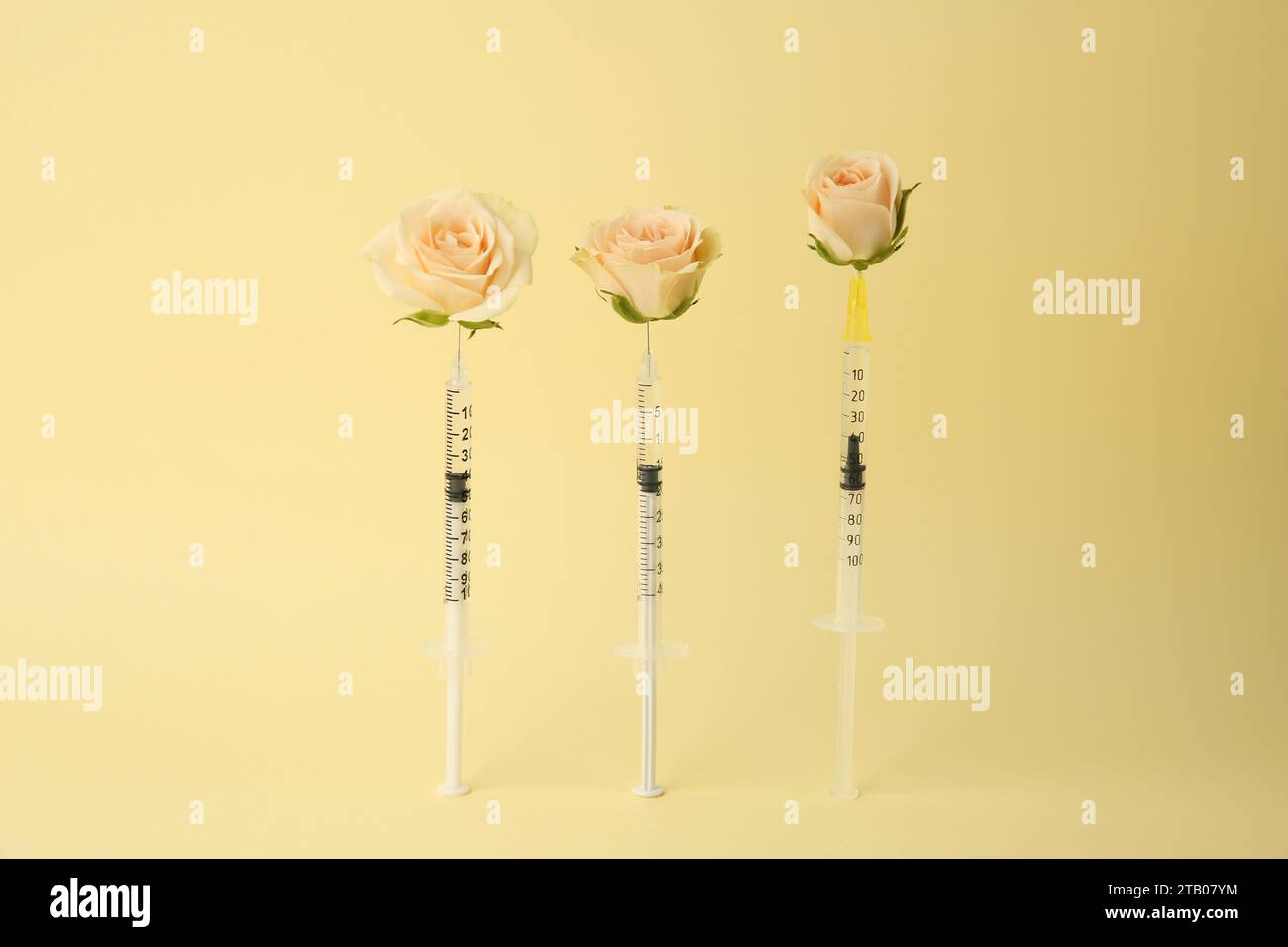 Medical syringes and rose flowers on pale yellow background Stock Photo ...