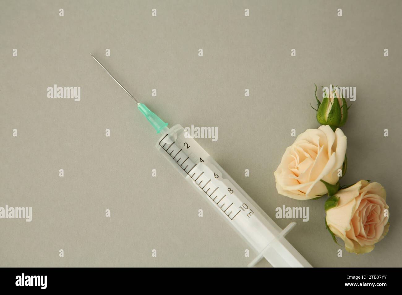Medical syringe and rose flowers on light grey background, flat lay ...