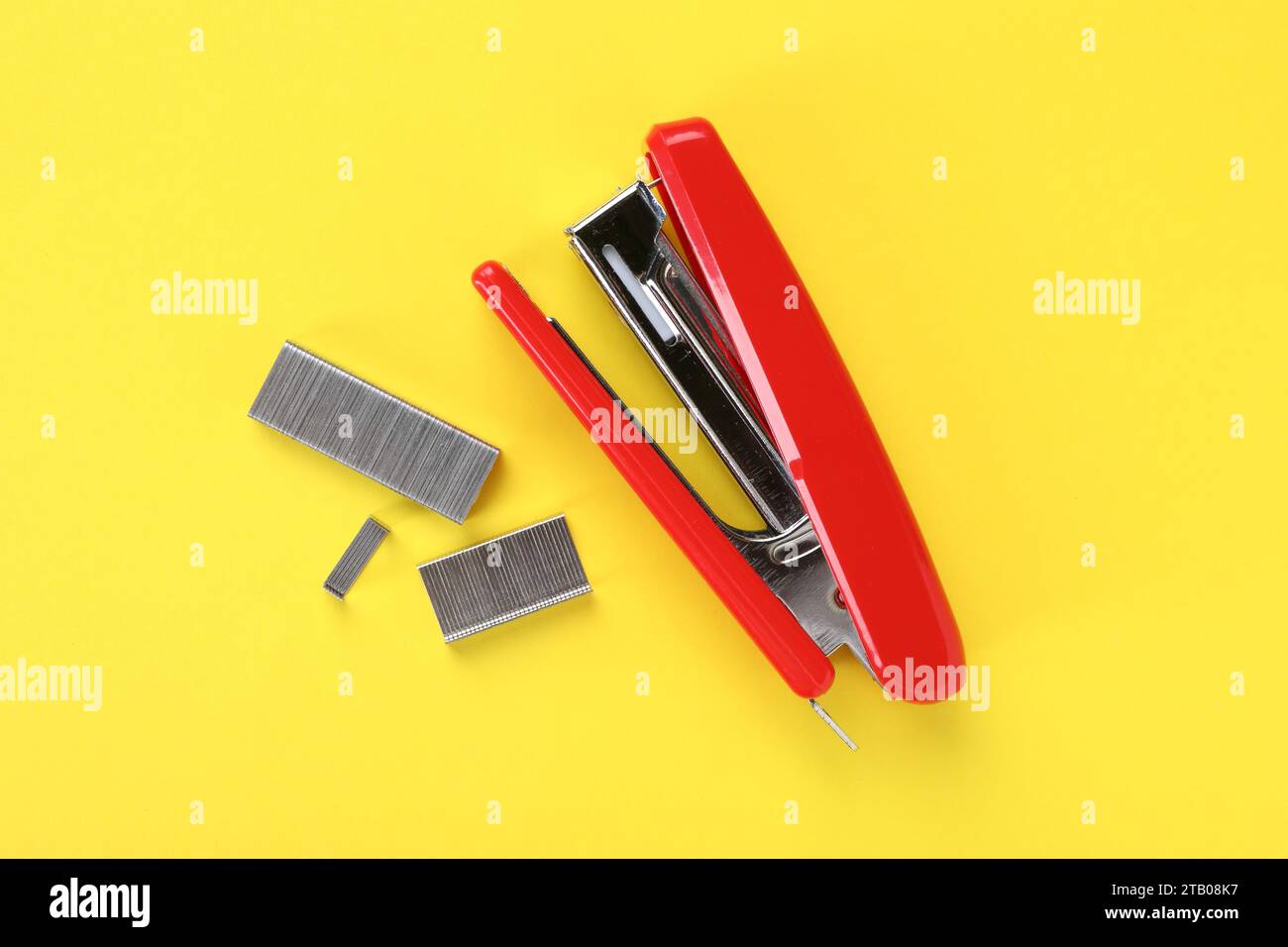 Red stapler with staples on yellow background, flat lay Stock Photo - Alamy