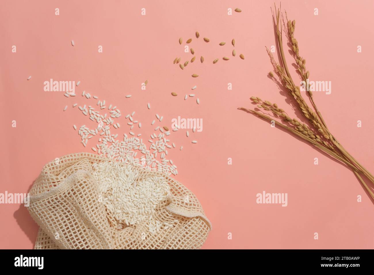 A mesh fabric basket and white rice on a pink background. Free space ...
