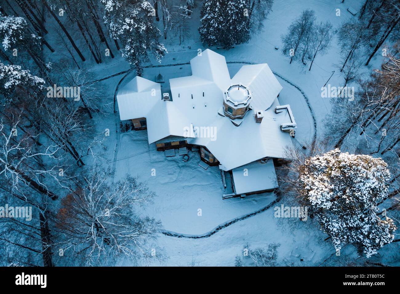 An old manor house with a roof covered with snow in the middle of a ...