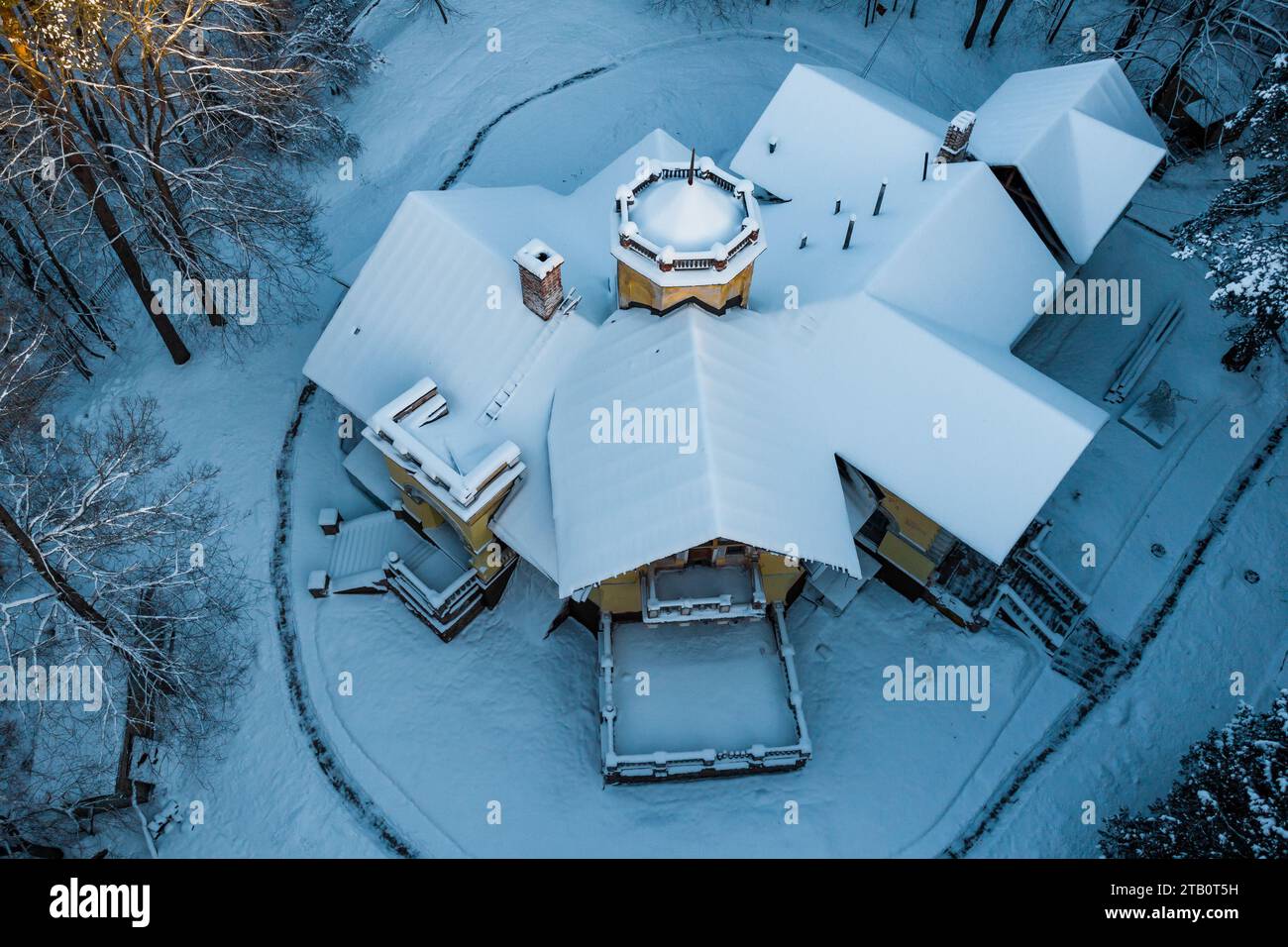 An old manor house with a roof covered with snow in the middle of a ...