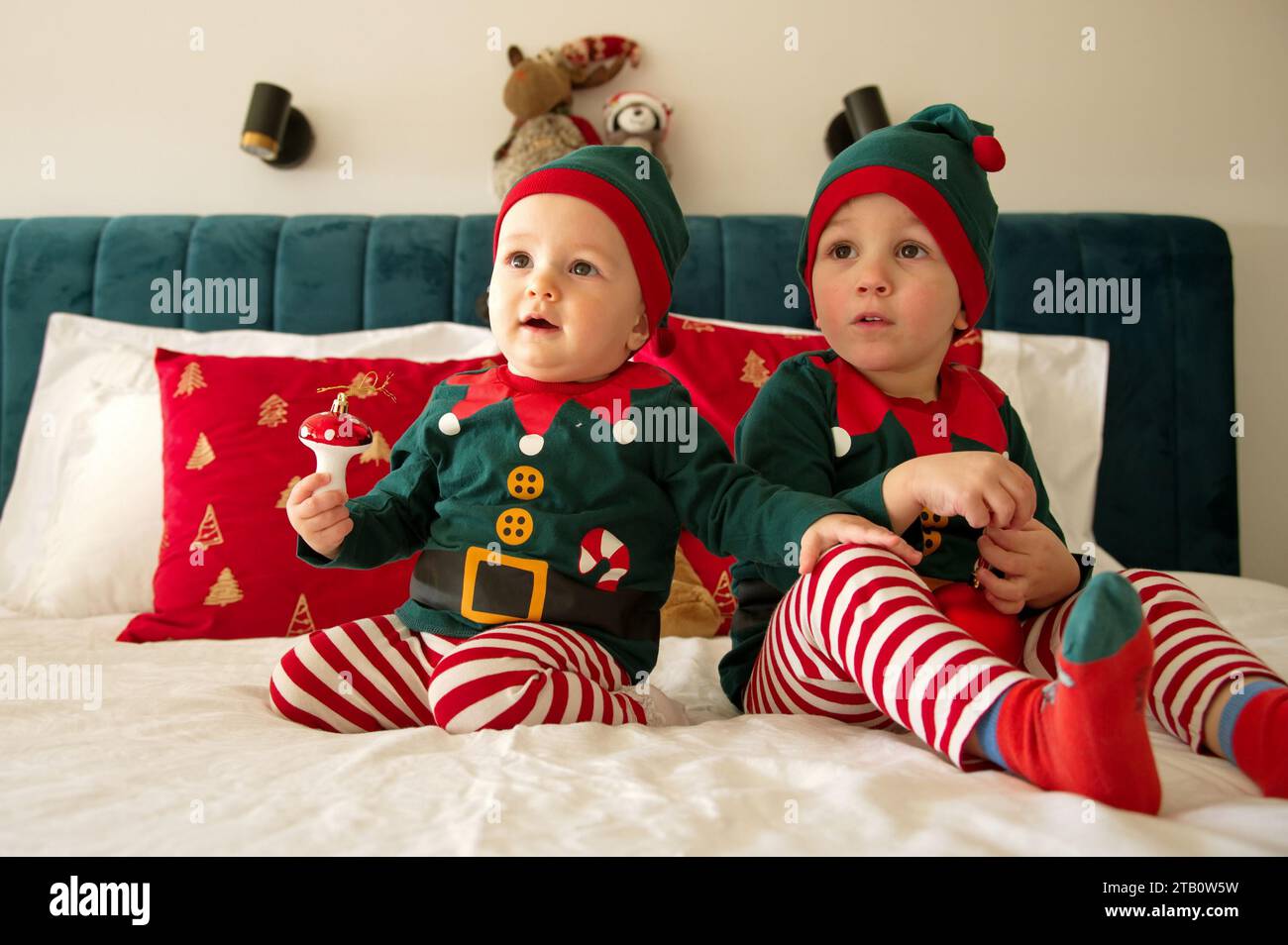 Baby girl and toddler dressed as elves sitting on a bed Stock Photo - Alamy