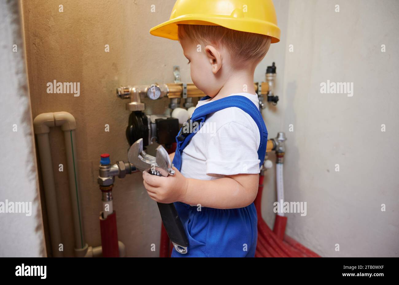 Boy using wrench tool while fixing plumbing installation with pipes and ...