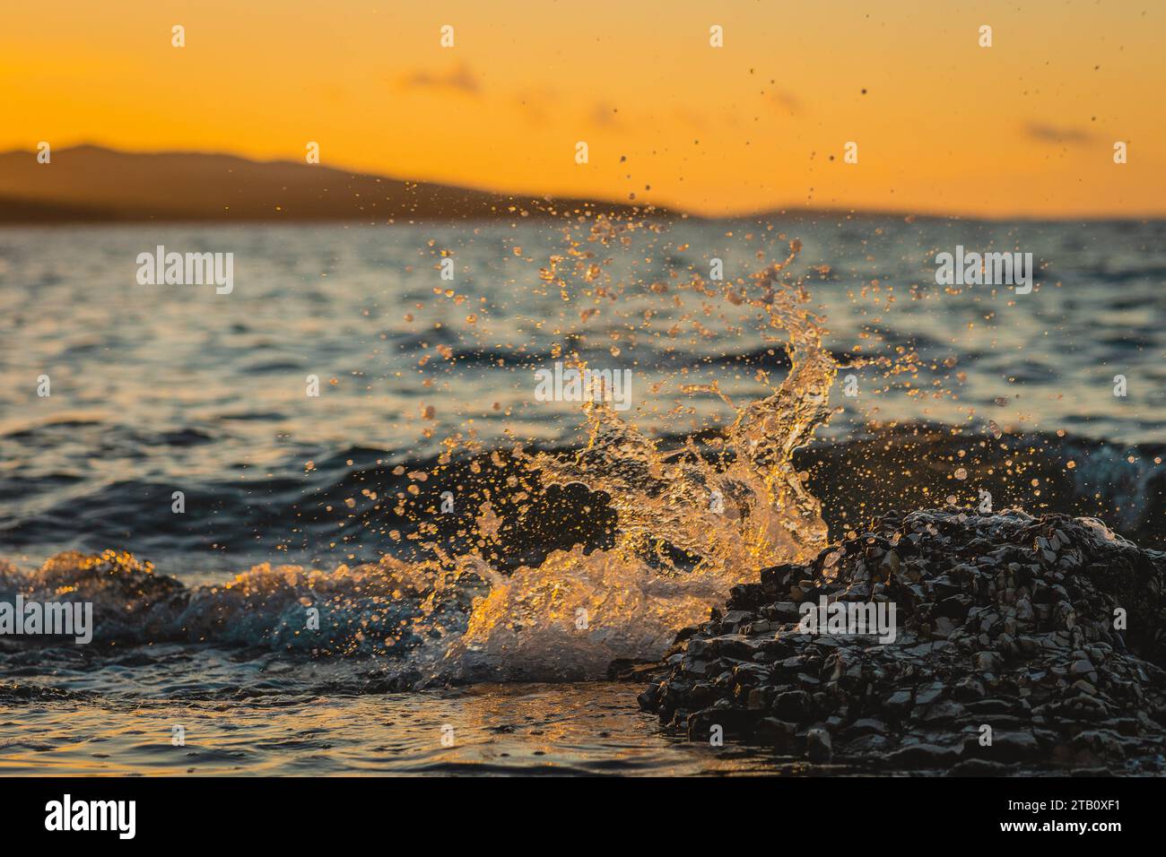 Waves splashing in the air on a peaceful lonely beach at sunrise ...