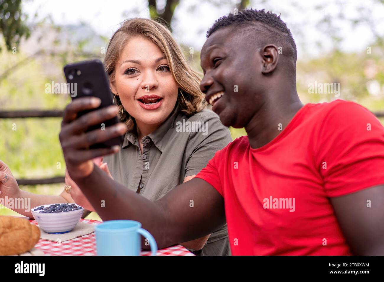 A multicultural couple shares a joyful moment over a smartphone ...
