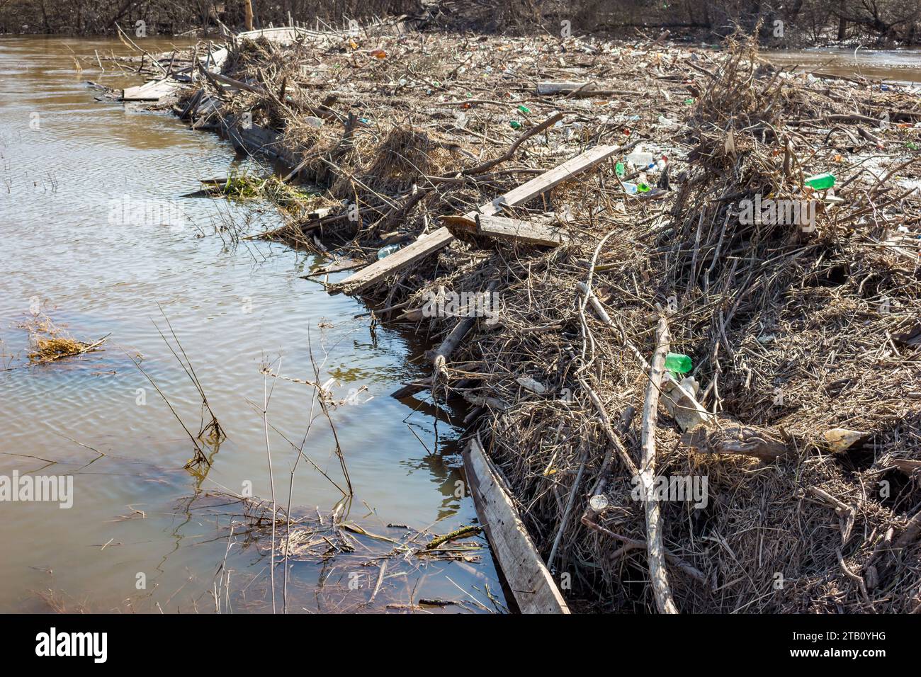 A large garbage jam blocking the riverbed with a pile of dry branches ...