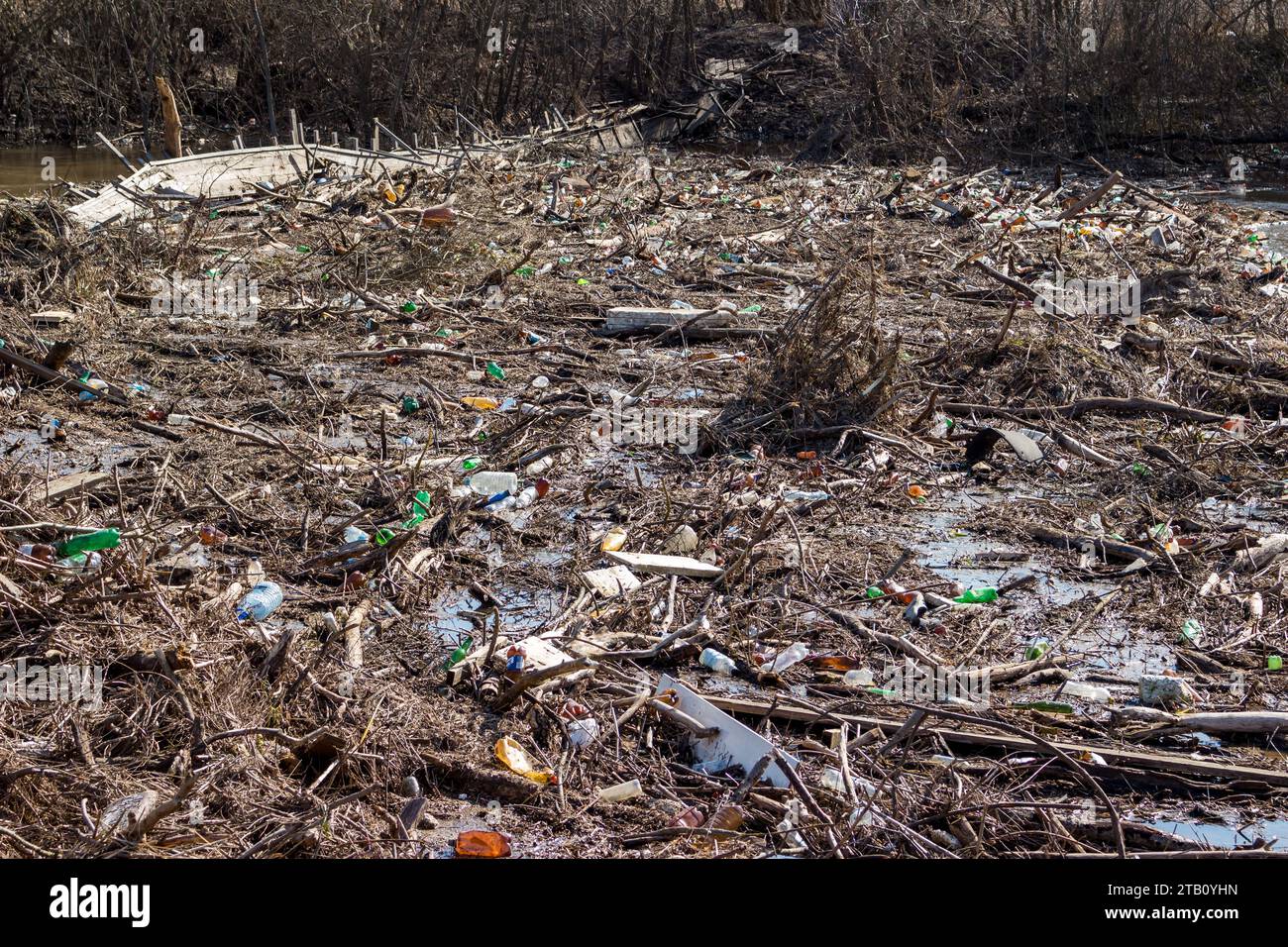 A large garbage jam blocking the riverbed with a pile of dry branches ...