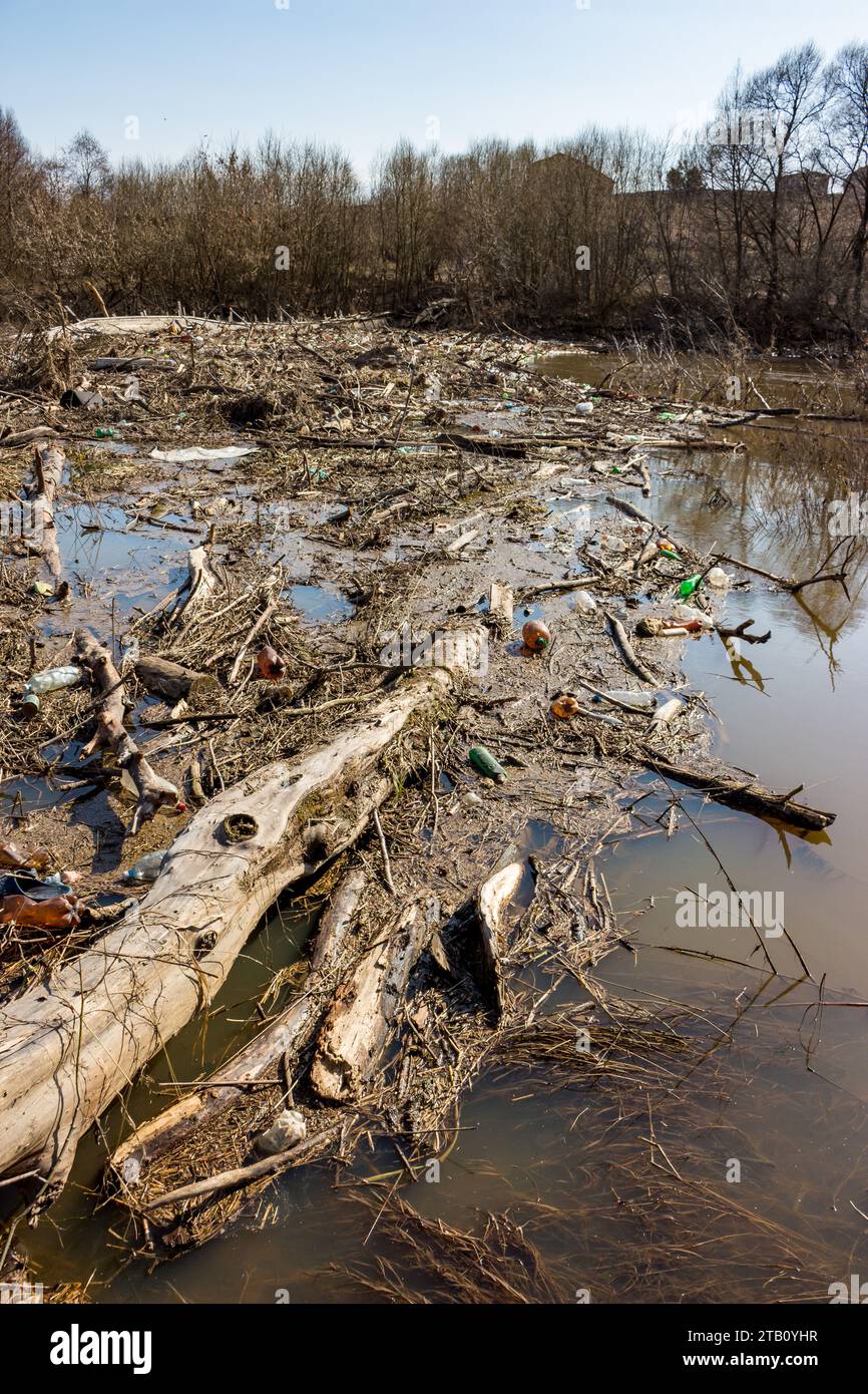A large garbage jam blocking the riverbed with a pile of dry branches ...