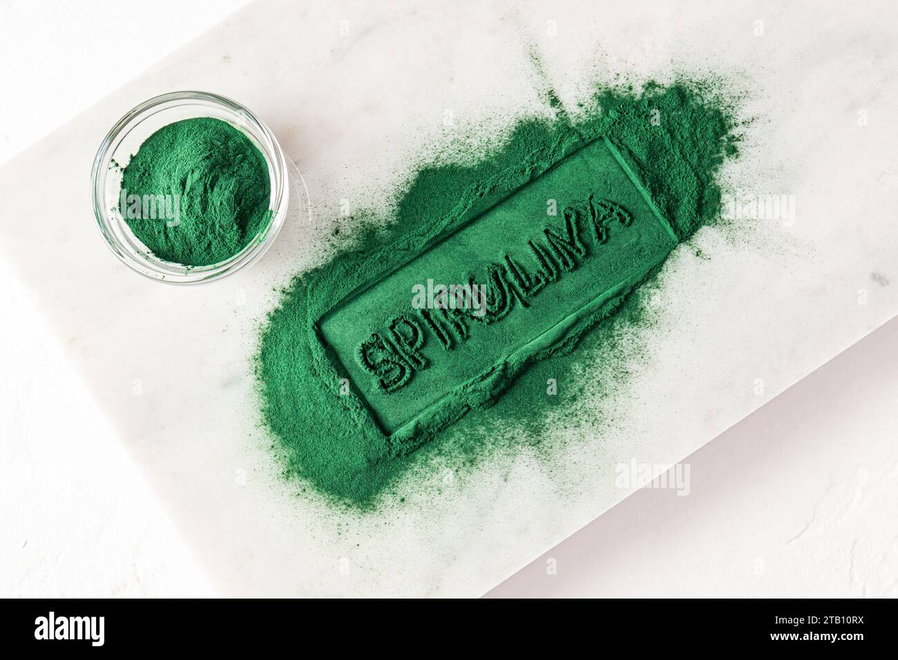 Inscription of green powder of natural spirulina algae on a white slice ...