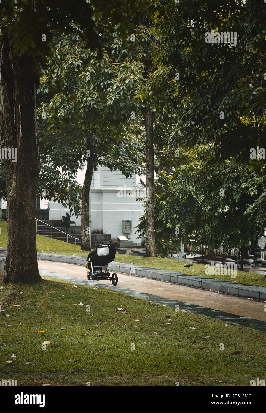 An empty baby stroller left alone on a pathway in a park in the city ...