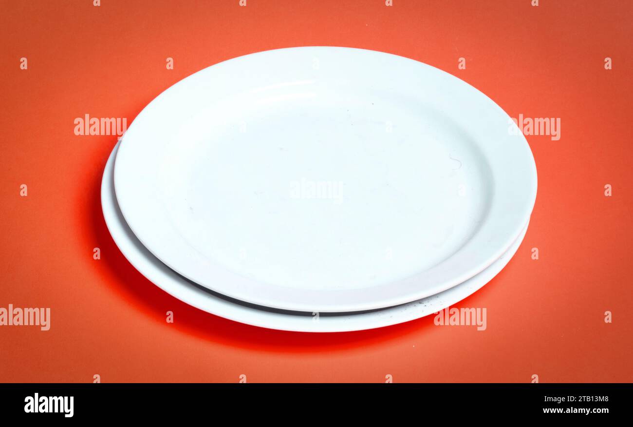 Two white plates on a solid red background Stock Photo - Alamy