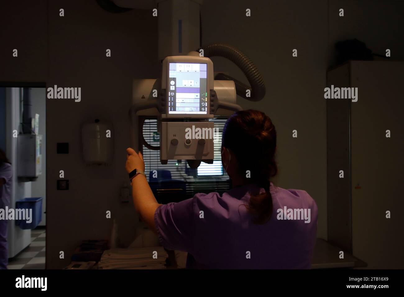 A female nurse diligently examining a medical device in a hospital ...